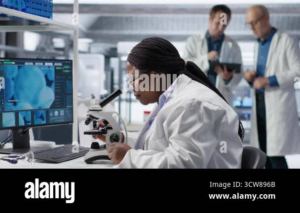 Woman working with microscope and sample tray in chemistry lab ...
