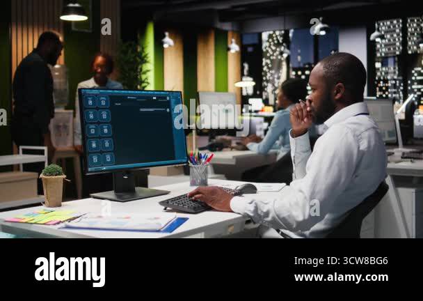 Young man PC user interacting with AI chat system on pc at office late at night, highlighting ...