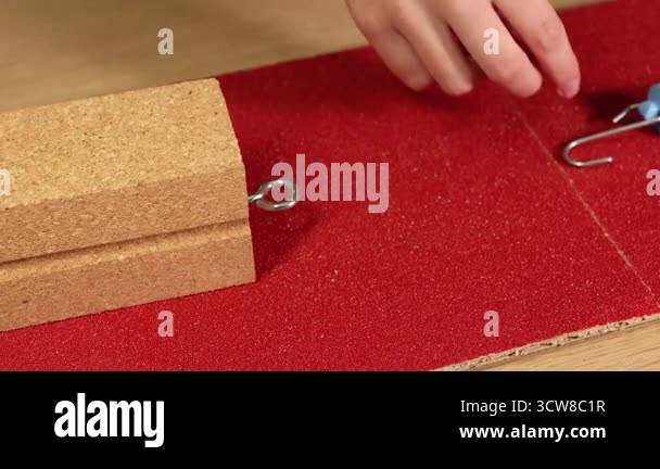 A hand uses a spring scale to measure friction on a wooden block over ...