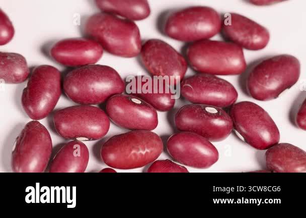 Close-up of red bean seeds scattered on a white background, showcasing ...