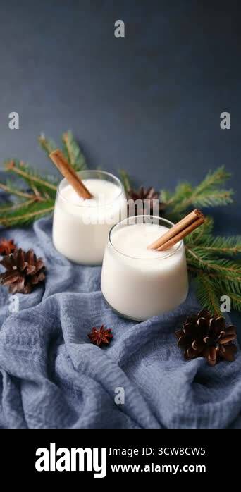 Creamy winter drinks with cinnamon sticks and pine sprigs on blue ...