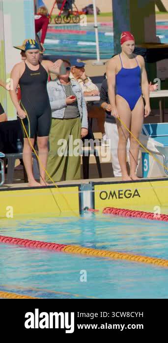 Two young women in swimsuits stand poolside with throw ropes, preparing ...