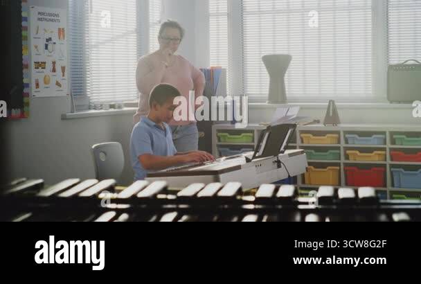 Music Teacher Guiding Primary School Boy to Play Piano in Music Class ...