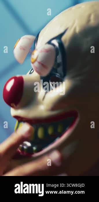 Creepy clown mask with red nose and yellow teeth shot from the side ...
