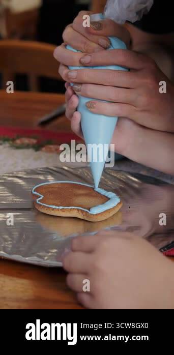 A close-up of a female pastry chef teaching a child how to decorate ...