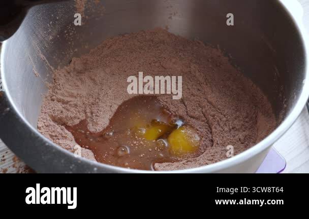 Mixing dry and wet ingredients in deep steel bowl closeup. Pouring out ...