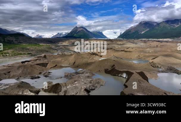 Ice melts in the valley of Alaska, USA. Fluffy clouds cover the tops of ...