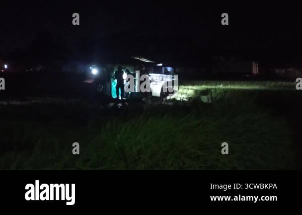 Rice harvesting at night using modern combine harvester, glowing ...