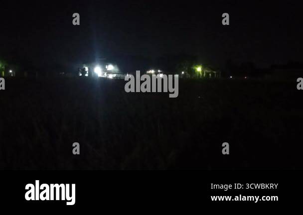 Rice harvesting at night using modern combine harvester, glowing ...