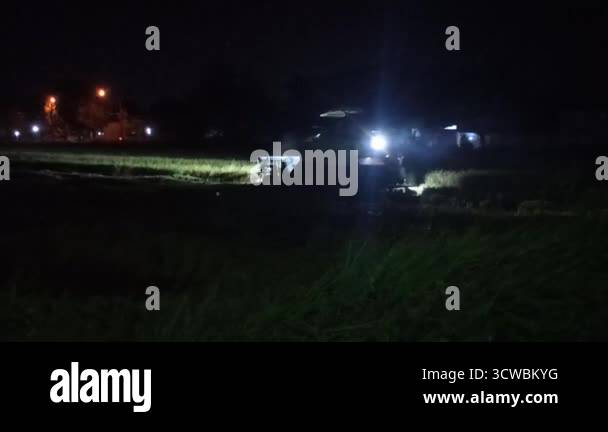 Rice harvesting at night using modern combine harvester, glowing ...
