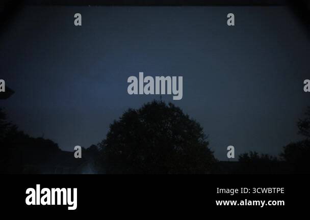 View of roof and tree tops at suburb street during the storm. Flashing ...