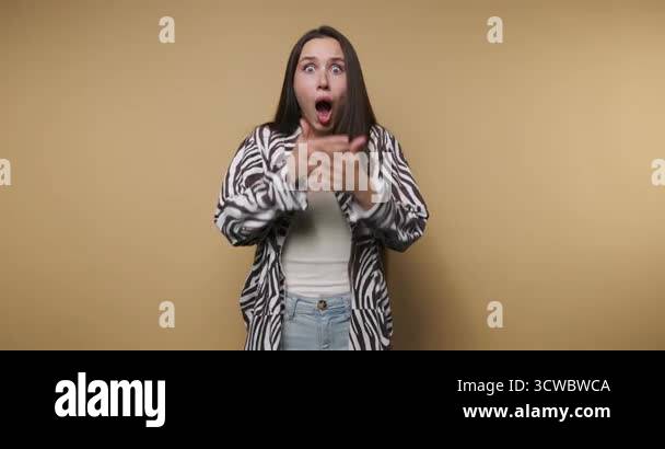 footage of young surprised woman is depicted with her hands covering ...