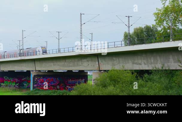 Train on modern concrete bridge with electric wires and colorful ...