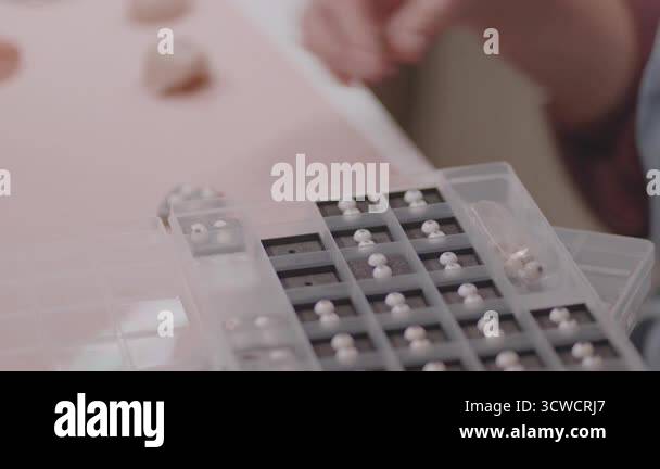 Artist picks out doll eyes from organized case focusing on fine details ...
