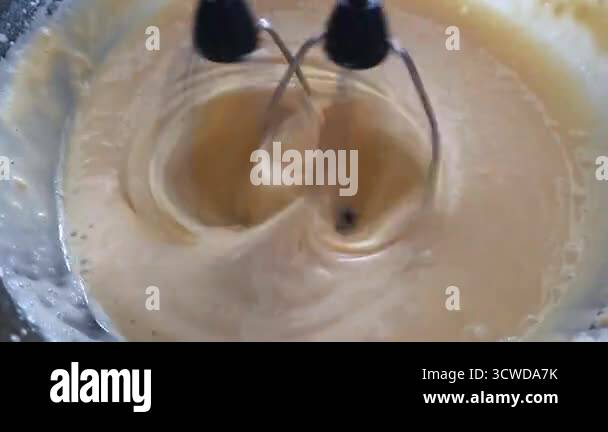 Electric beaters vigorously mix creamy batter, capturing a dynamic ...