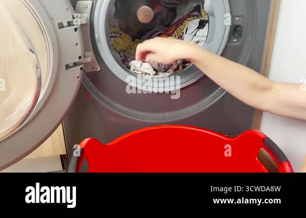 A woman takes out freshly washed and spun clothes from a washing ...