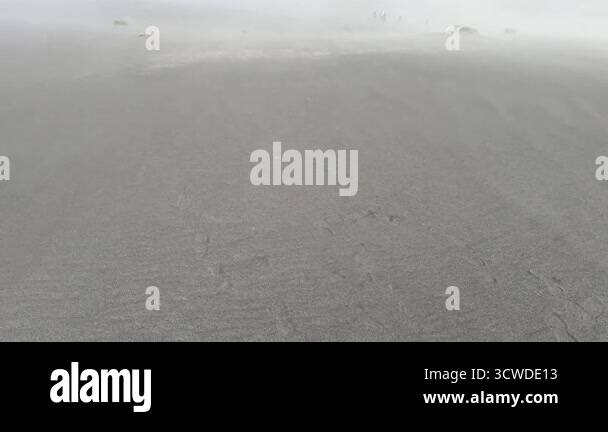 4k footage of strong wind gust creating a sand storm on grey sand. Wind ...