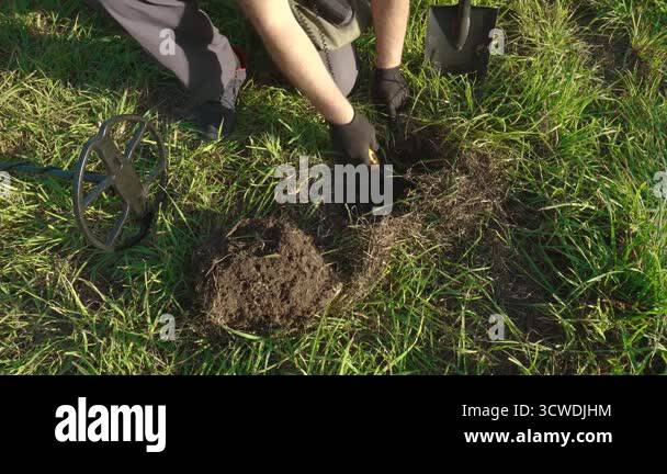 A person is actively digging in the earth with a spade while using a ...