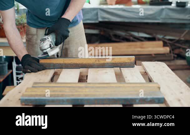 A worker is grinding rust off a steel part with an angle grinder. Close ...