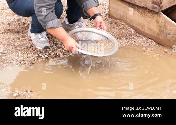 Person panning for gold in muddy water Stock Video Footage - Alamy