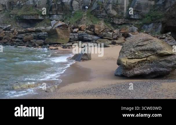 A wide, dramatic landscape photograph of a rugged seaside beach in ...