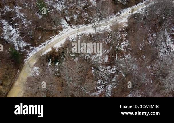 Three SUVs drive on a snowy, muddy mountain road. Winter driving ...