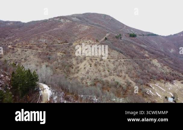 Aerial view of winding dirt road on mountainside. Hikers enjoy scenic ...