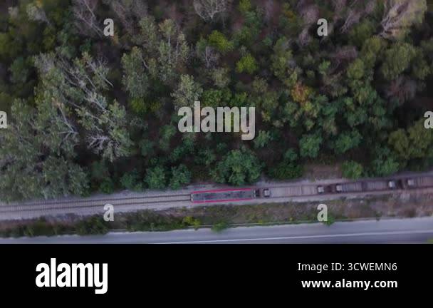 Aerial view of a train moving along a railway track beside a road ...