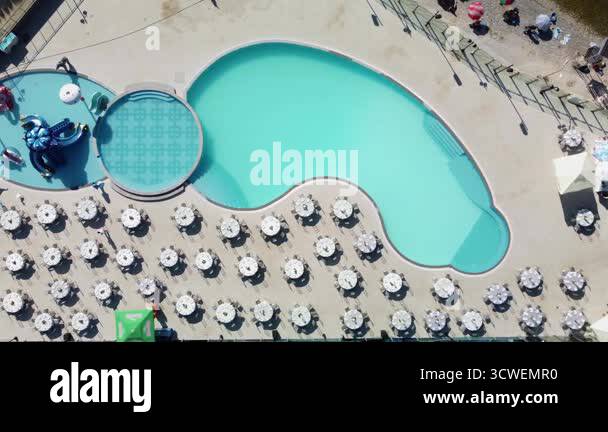 An aerial view of a kidney-shaped swimming pool, round kiddie pool, and ...