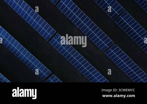 Aerial view of a solar power plant at dusk. The dark landscape is ...