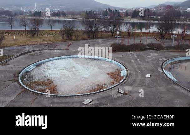 Two abandoned, round swimming pools, one empty and one with dirty water ...