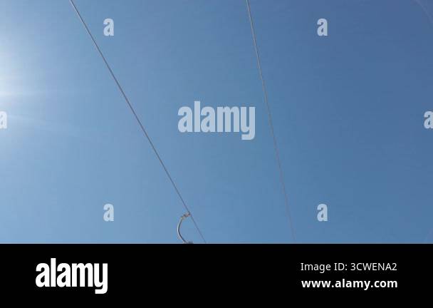 T-bar ski lift ascends into a clear blue sky on a bright, sunny winter ...