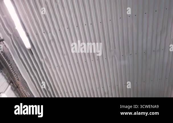 Lines of shiny metal reflect bright lights while vapors rise in a ...