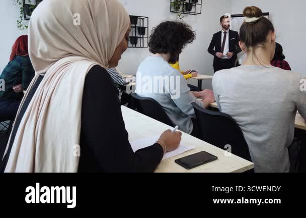 Diverse young students learning, taking notes, and engaging with their ...