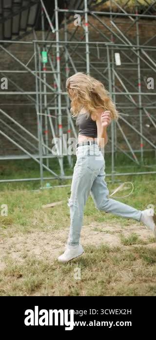 A young girl runs and jumps energetically at a construction site ...