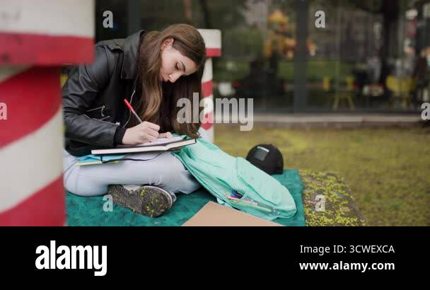 Focused Teen Girl Student Writing in Notebook in City Park During ...