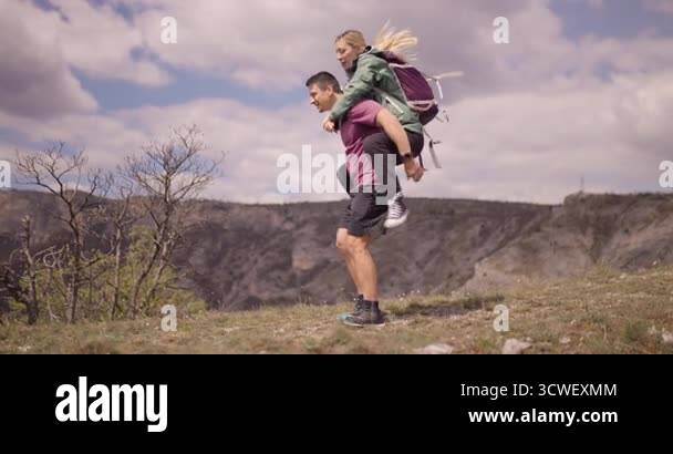 Two friends having fun outdoors with a joyful piggyback ride against a ...