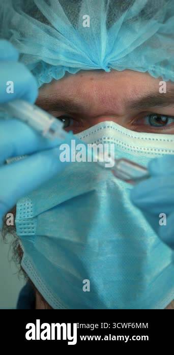 Male doctor in protective medical hat, gloves and mask holding syringe ...