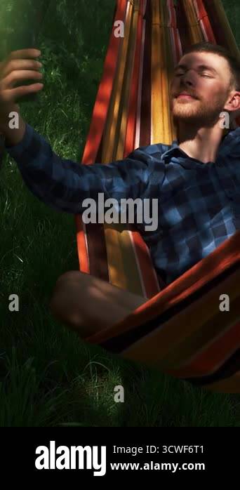 Young man taking selfie photo with mobile phone lying on hammock. Male ...