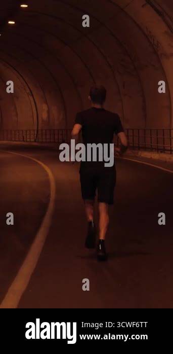 Male athlete running through empty tunnel in high mountain range. Man ...