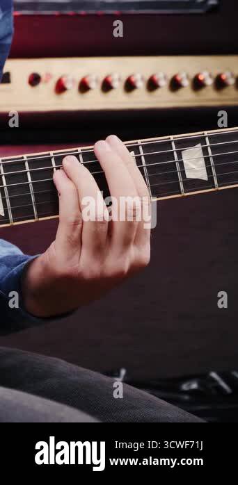 Male hands are playing on guitar strings. Guitarist plays on electric ...