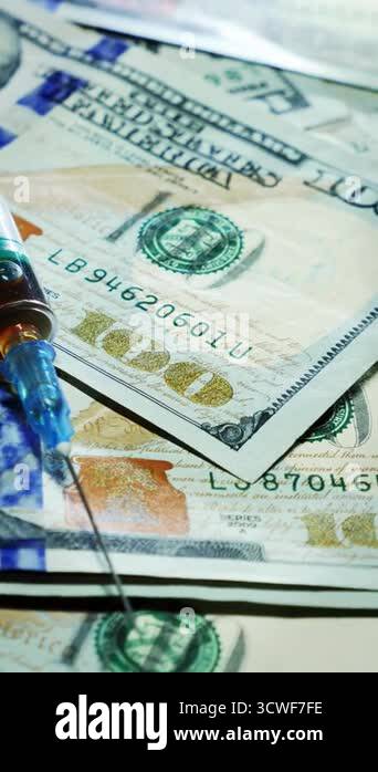 Filled syringe rotating on cash money background, close up. Medicine ...