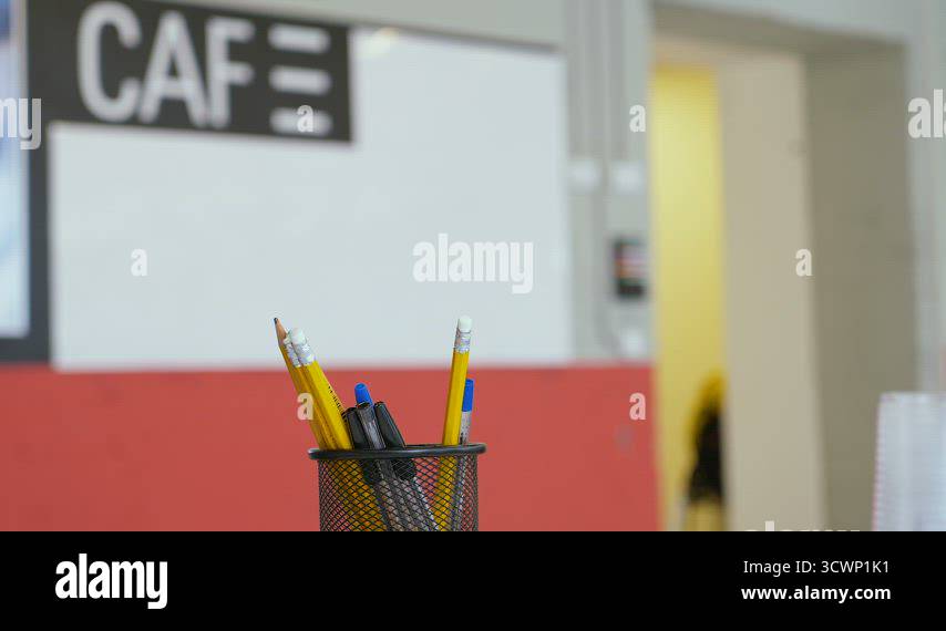 Close up on a metal black box with pencils and pens in the classroom ...