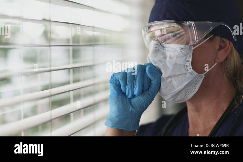 Stressed Doctor or Nurse On Break At Window Removing PPE, Face Mask and ...
