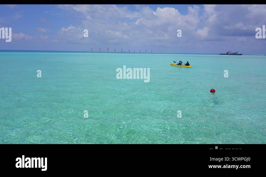 A couple on a yellow sea kayak paddling on the crystal clear water at ...