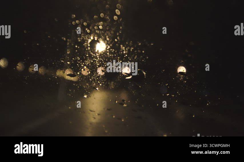 Rain drops on car windshield. Abstract street lights in the background ...