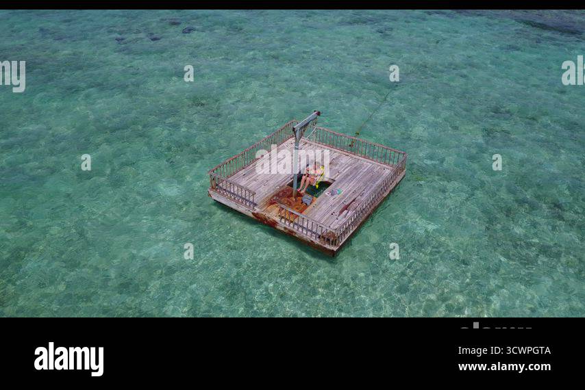 A rustic wooden water raft floating on the crystal clear water anchored ...