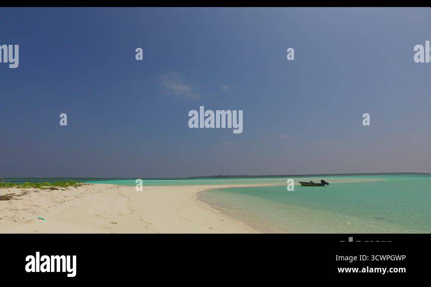 A small boat anchored at the sand bar of a beach with flat powdery ...