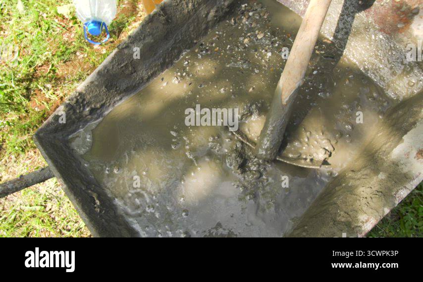 outdoor mixing cement, water and sand with small rocks to create ...