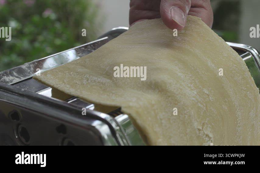 Stretching home made dough on a rolling machine. Preparation of thin ...
